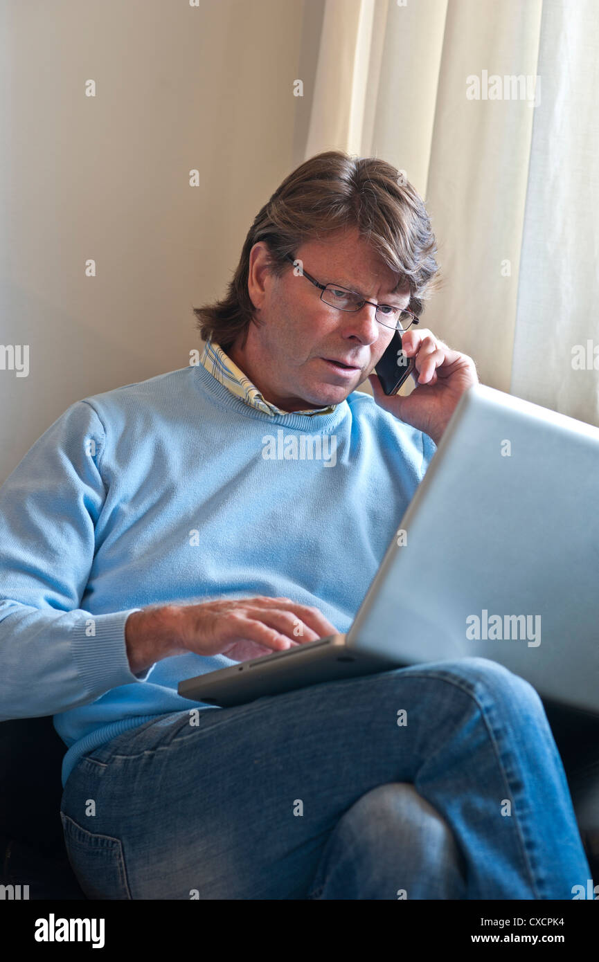 Mature man at home checking screen information on his laptop computer ...