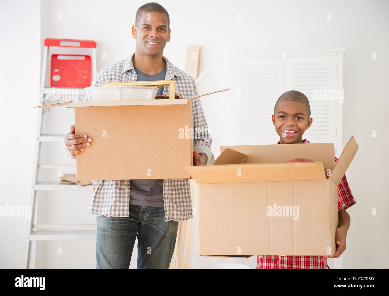 Father and son holding moving boxes Stock Photo - Alamy
