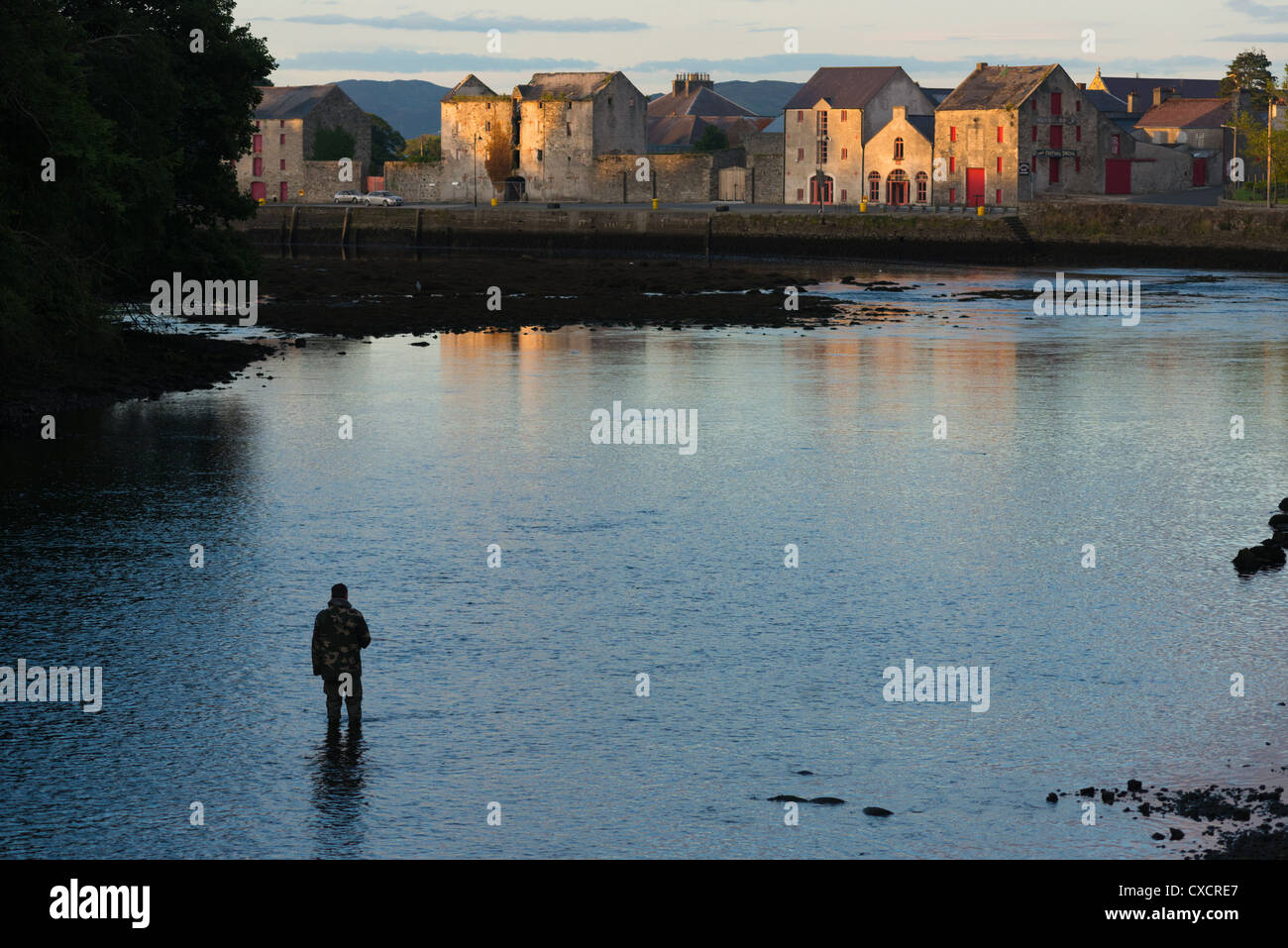 Man fishing with view of warehouses on the waterfront, Ramelton, County ...