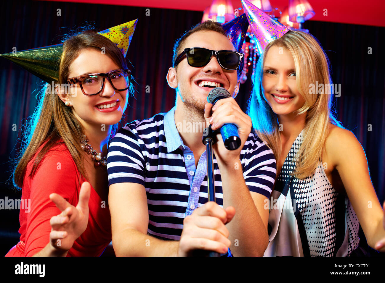 Portrait of happy friends singing in microphone in the karaoke bar ...