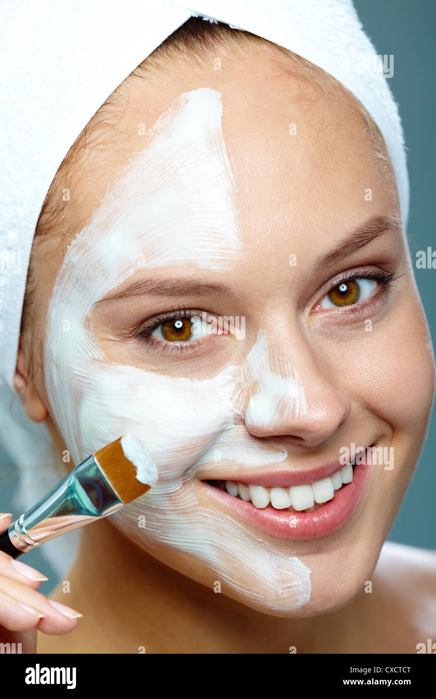 Fresh woman applying facial mask onto her face with brush Stock Photo ...