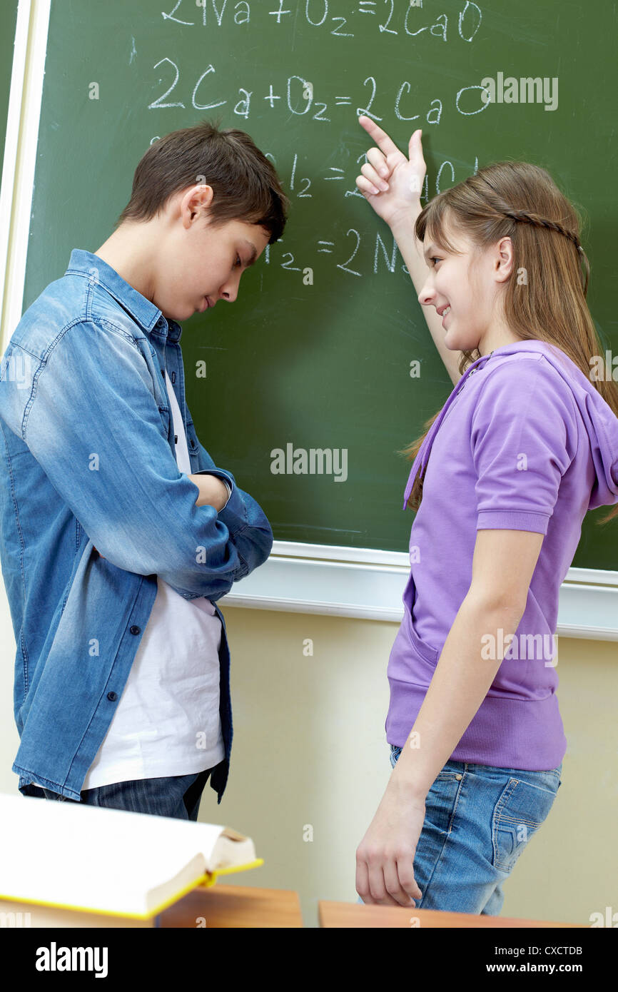 Clever girl pointing at blackboard while explaining formula to ...