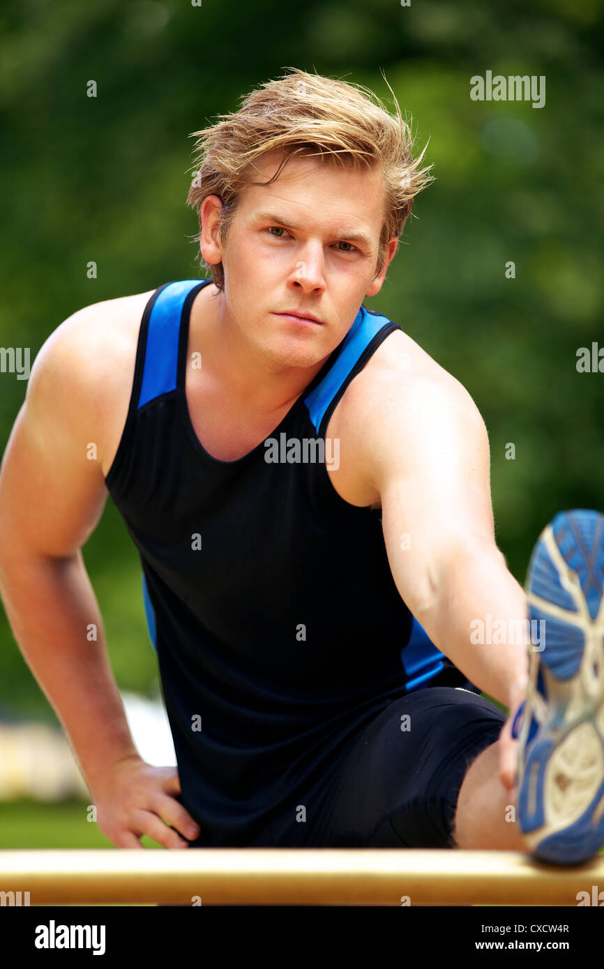 Handsome guy warming up and doing stretching exercise before running ...