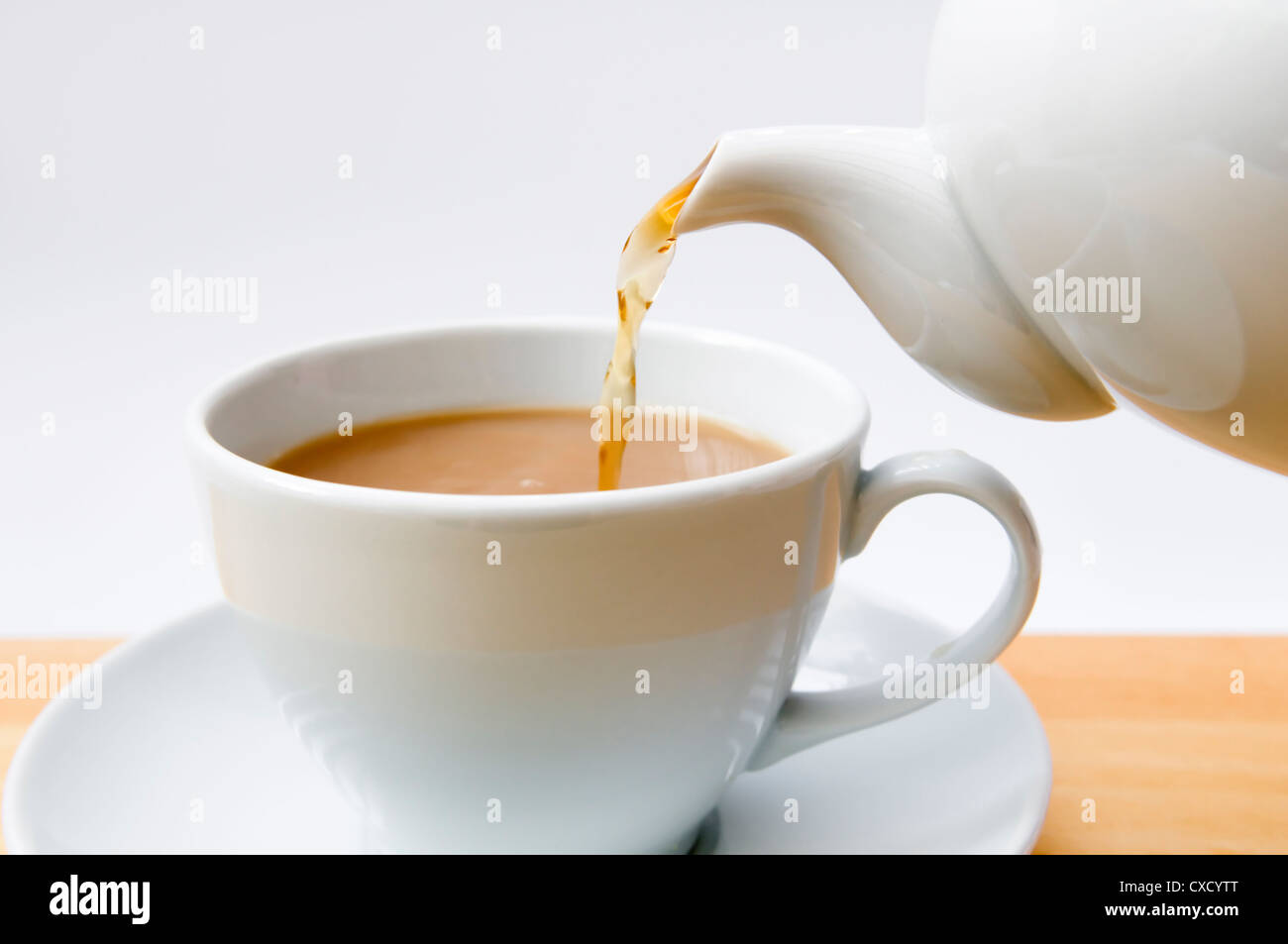 Pouring tea into tea cup on wooden table against white background Stock ...