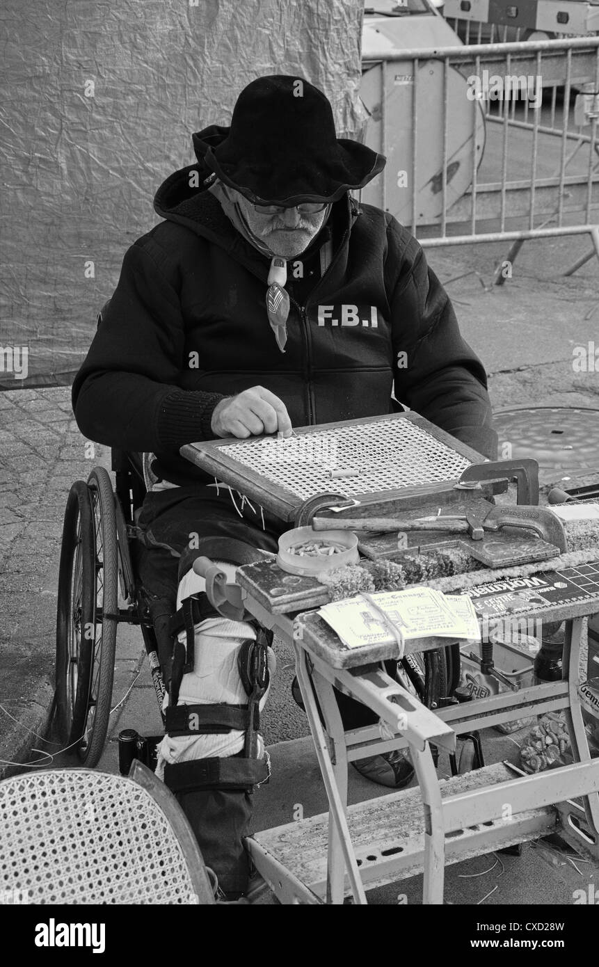 Craftsman cane worker occupied with repairing a chair in the street ...