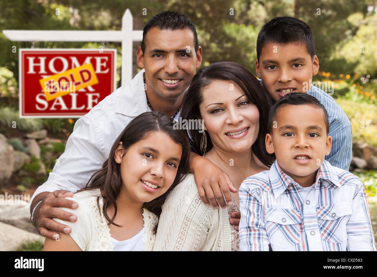 Happy Hispanic Family in Front of Sold Home for Sale Real Estate Sign ...