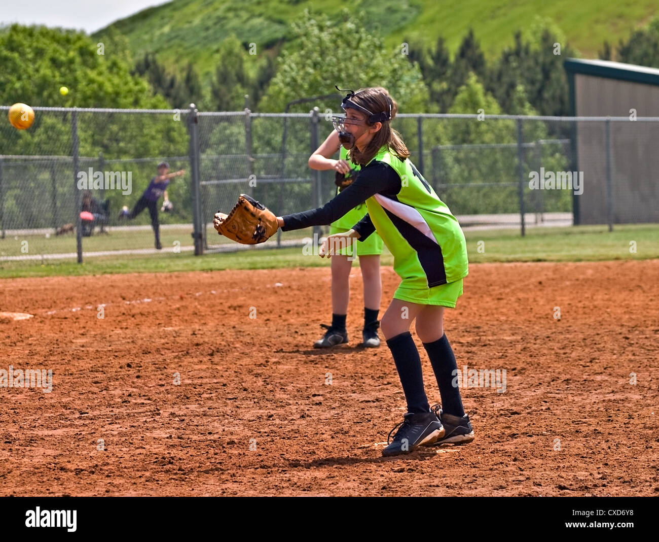 Young pitcher trying to catch a ball that was hit back at her during a ...