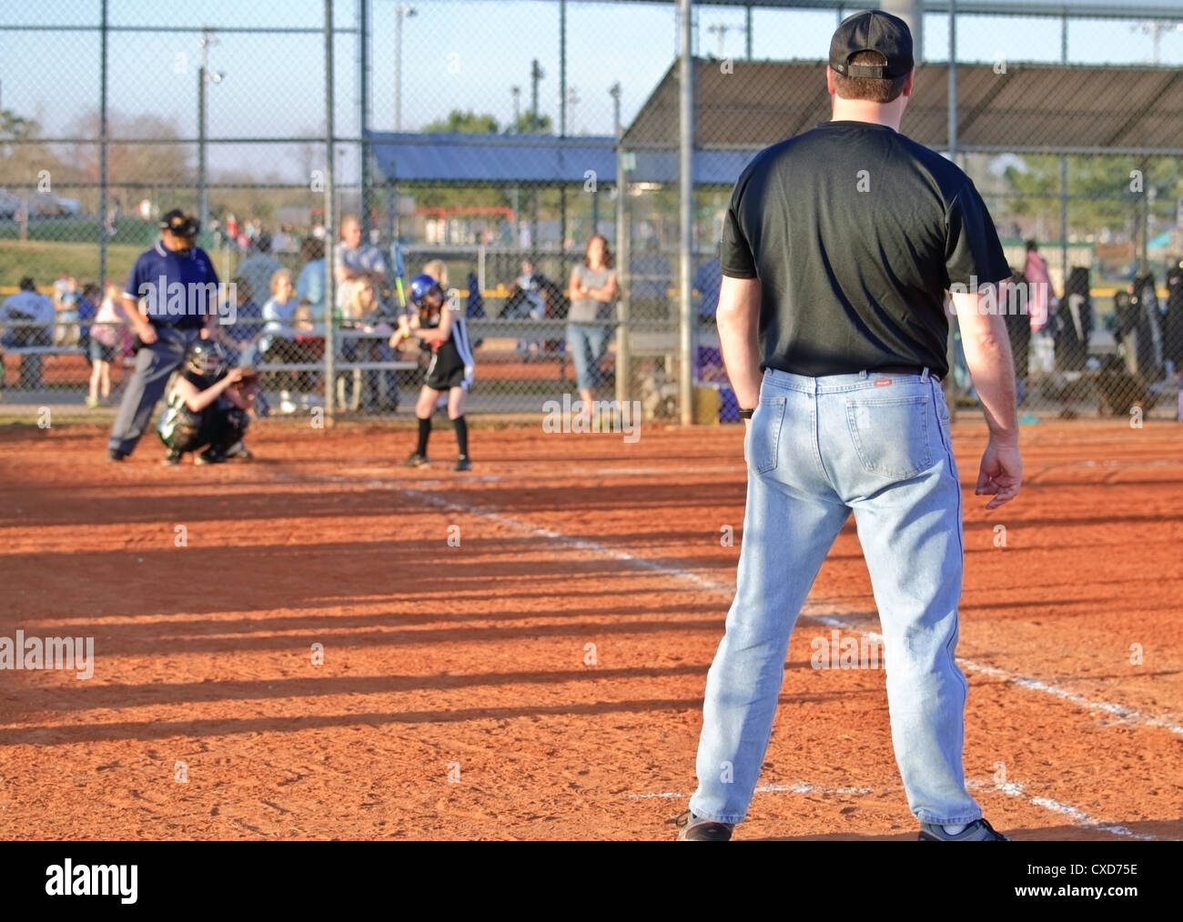 Action at home plate during a girl's softball game with the coach on ...