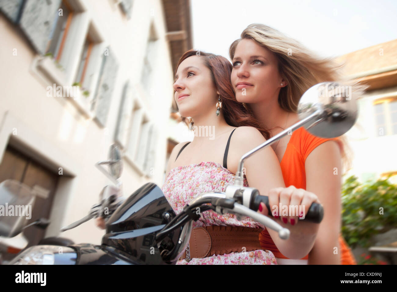 Caucasian friends riding scooter together Stock Photo - Alamy