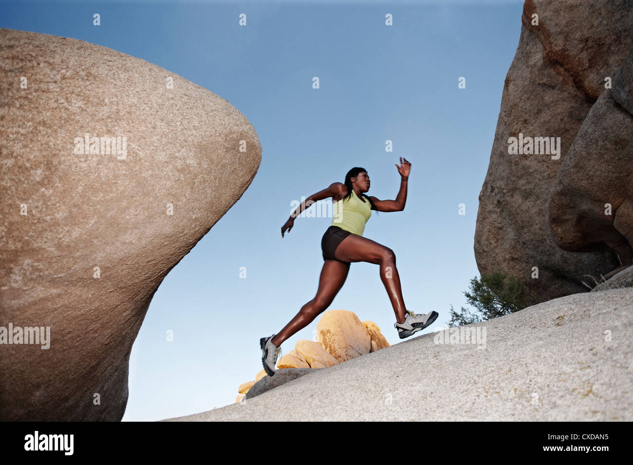 Woman running up boulder in remote area Stock Photo - Alamy