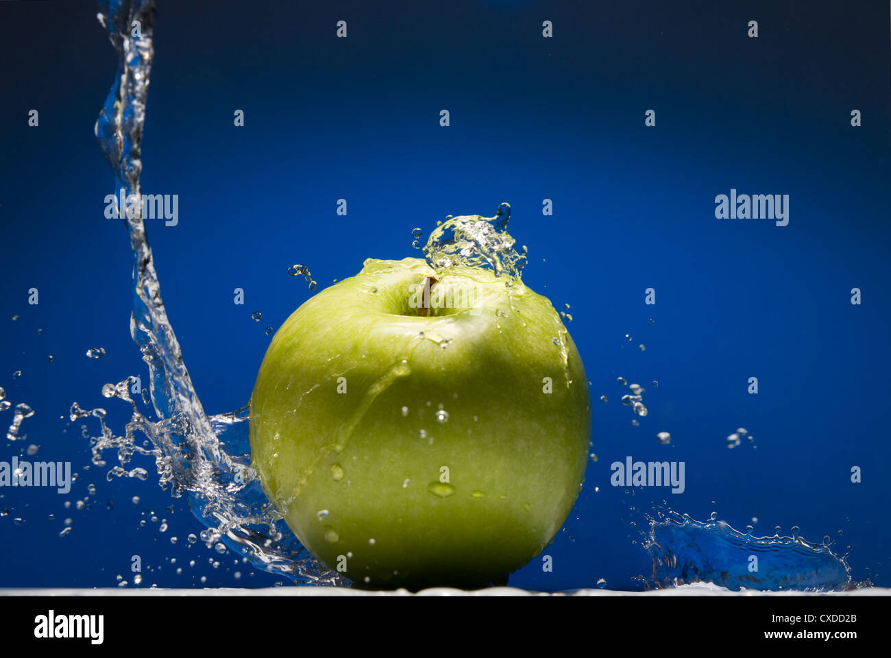Green apple with water splash on blue background Stock Photo - Alamy