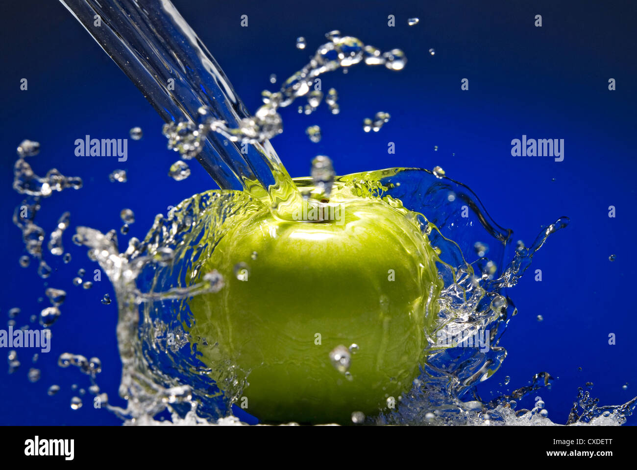 Green apple with water splash on blue background Stock Photo - Alamy
