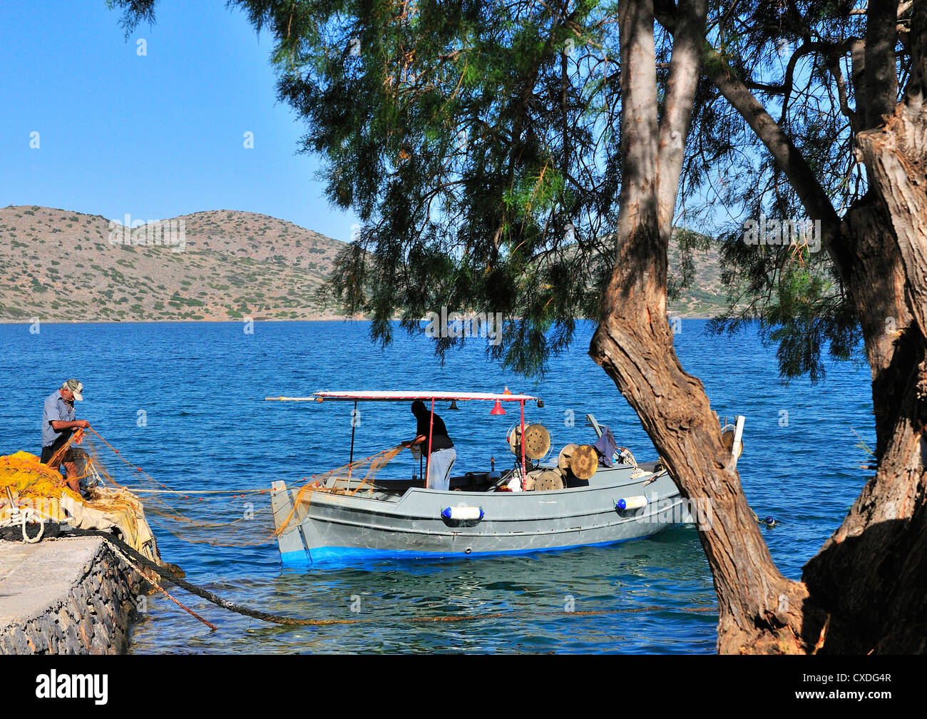 Two Cretan fishermen tending to and preparing fishing nets for the ...