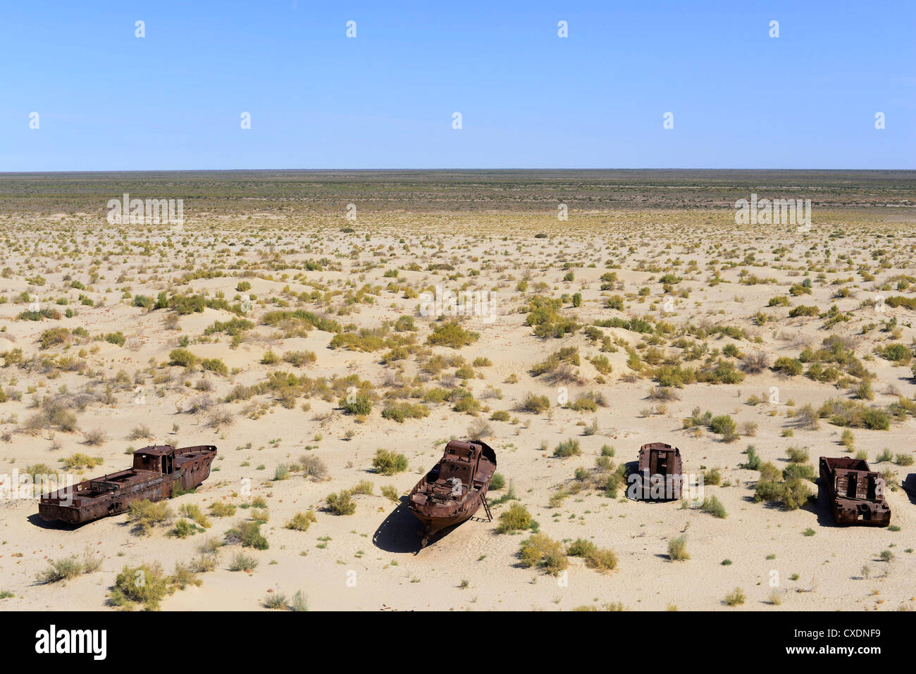 Rusty boats lay still on the dry desert sea bed of the dried Aral sea ...