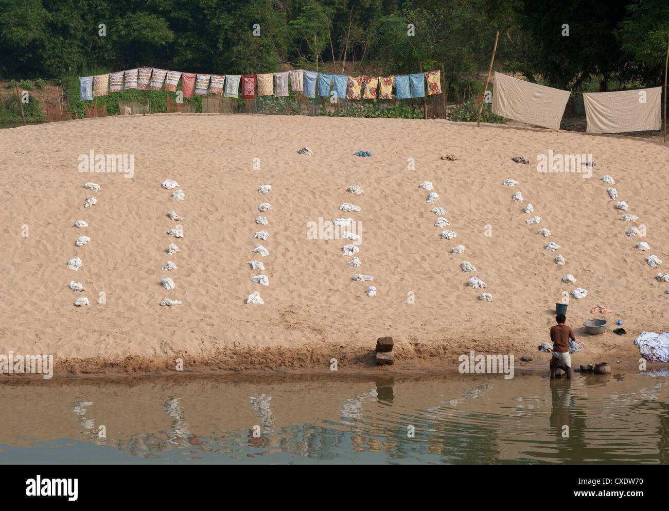 Dhobi wallah washing laundry in the river with very organised piles ...