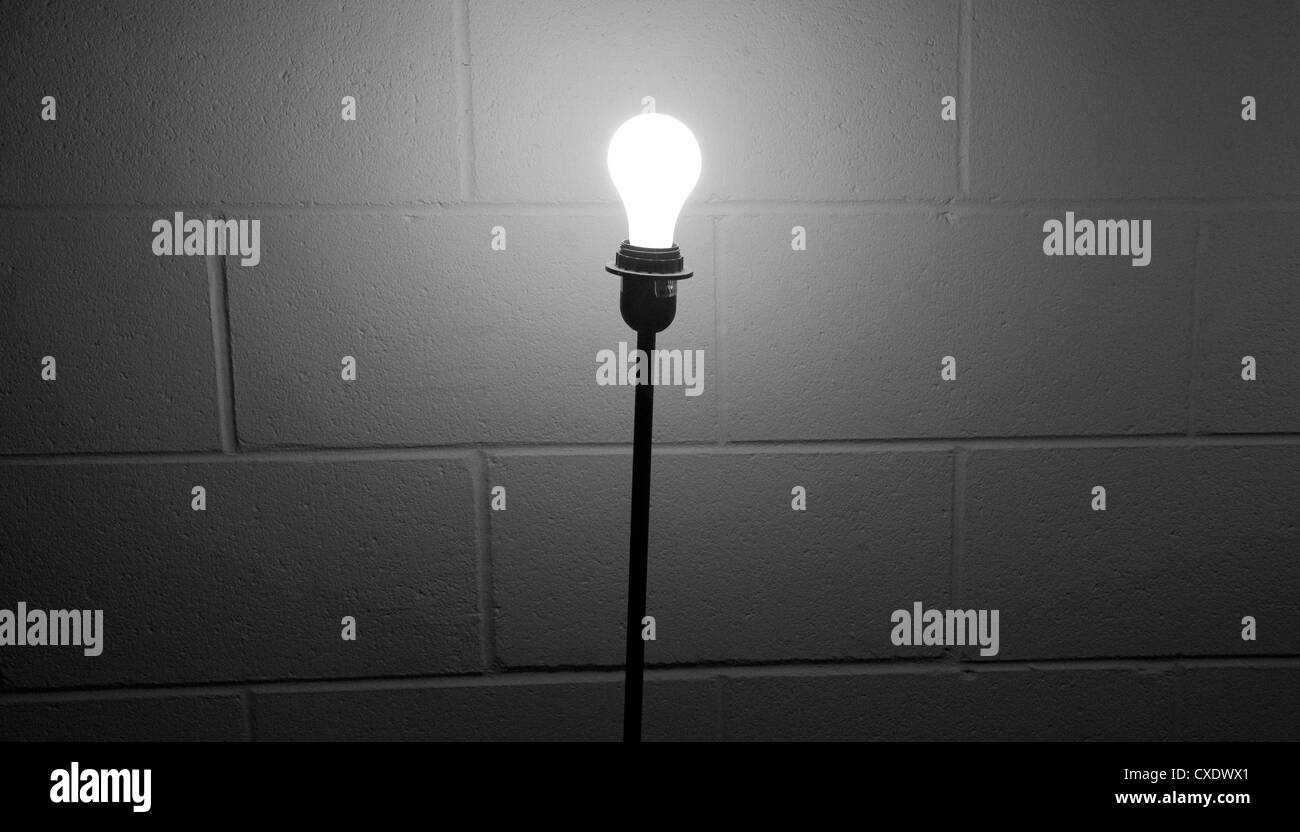 glowing electric bare light bulb in upright light fixture against a ...