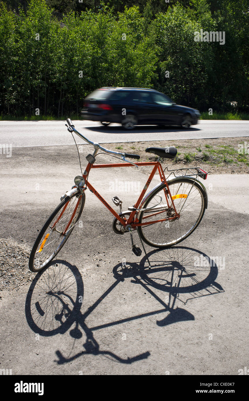 Bicycle casting shadow, car driving behind Stock Photo - Alamy
