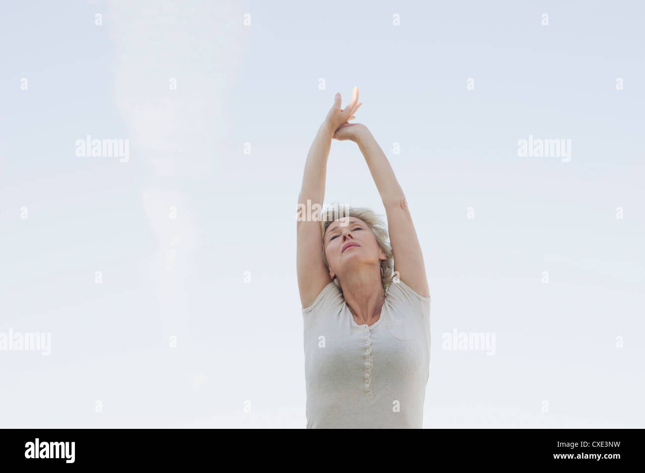 Mature woman stretching arms with arms closed Stock Photo - Alamy
