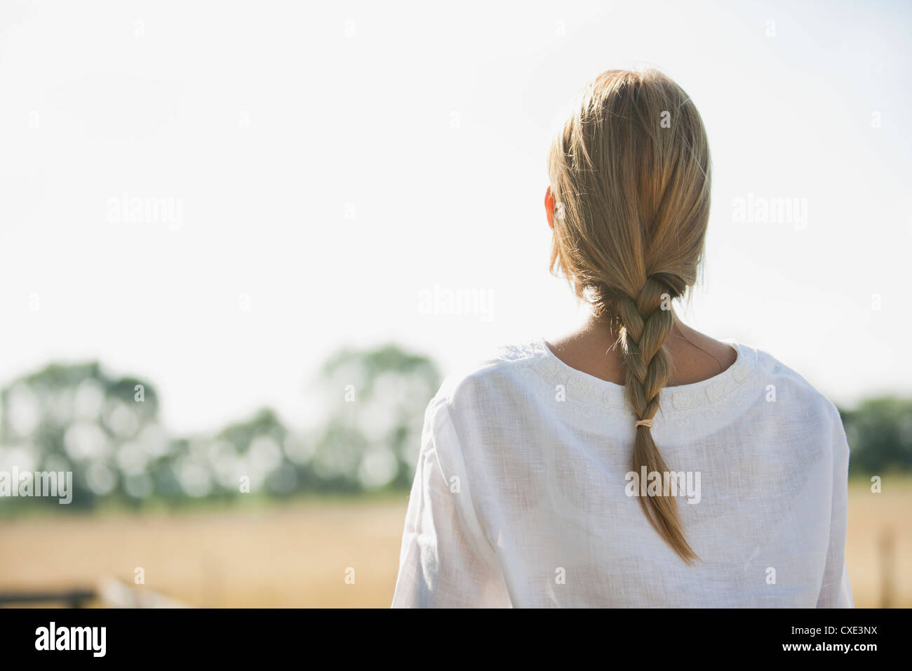 Mid-adult woman looking into distance at field, rear view Stock Photo ...