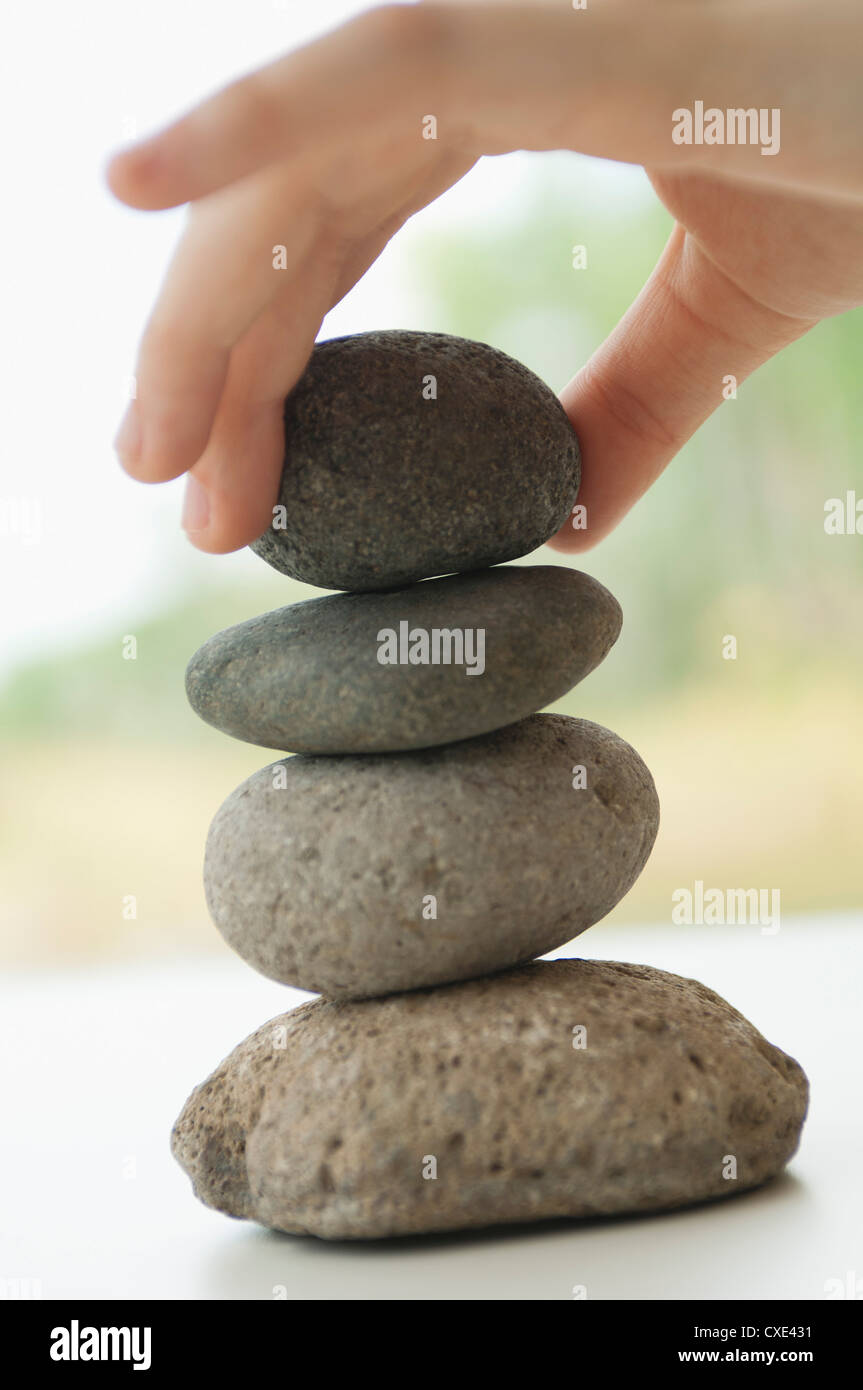 Hand stacking pebbles Stock Photo - Alamy