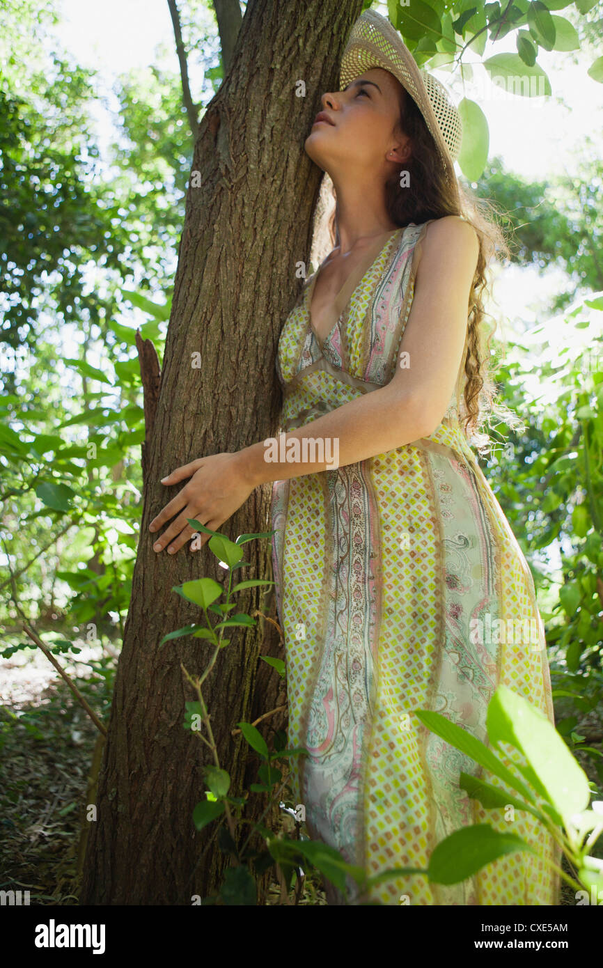 Young woman leaning against tree Stock Photo - Alamy
