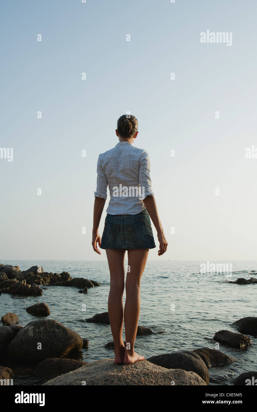 Girl standing on rock looking at ocean Stock Photo - Alamy