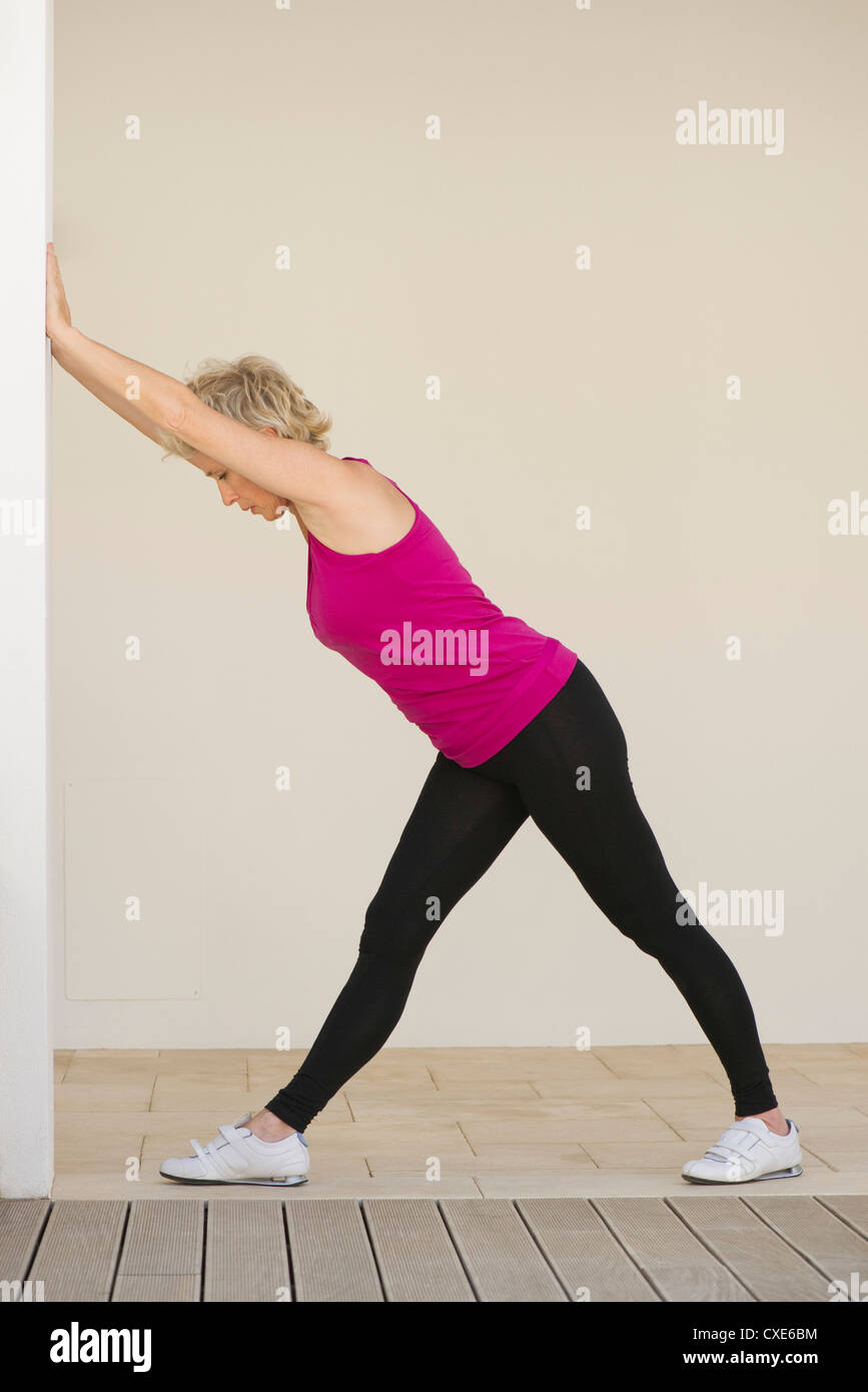 Mature woman pushing against wall, side view Stock Photo - Alamy