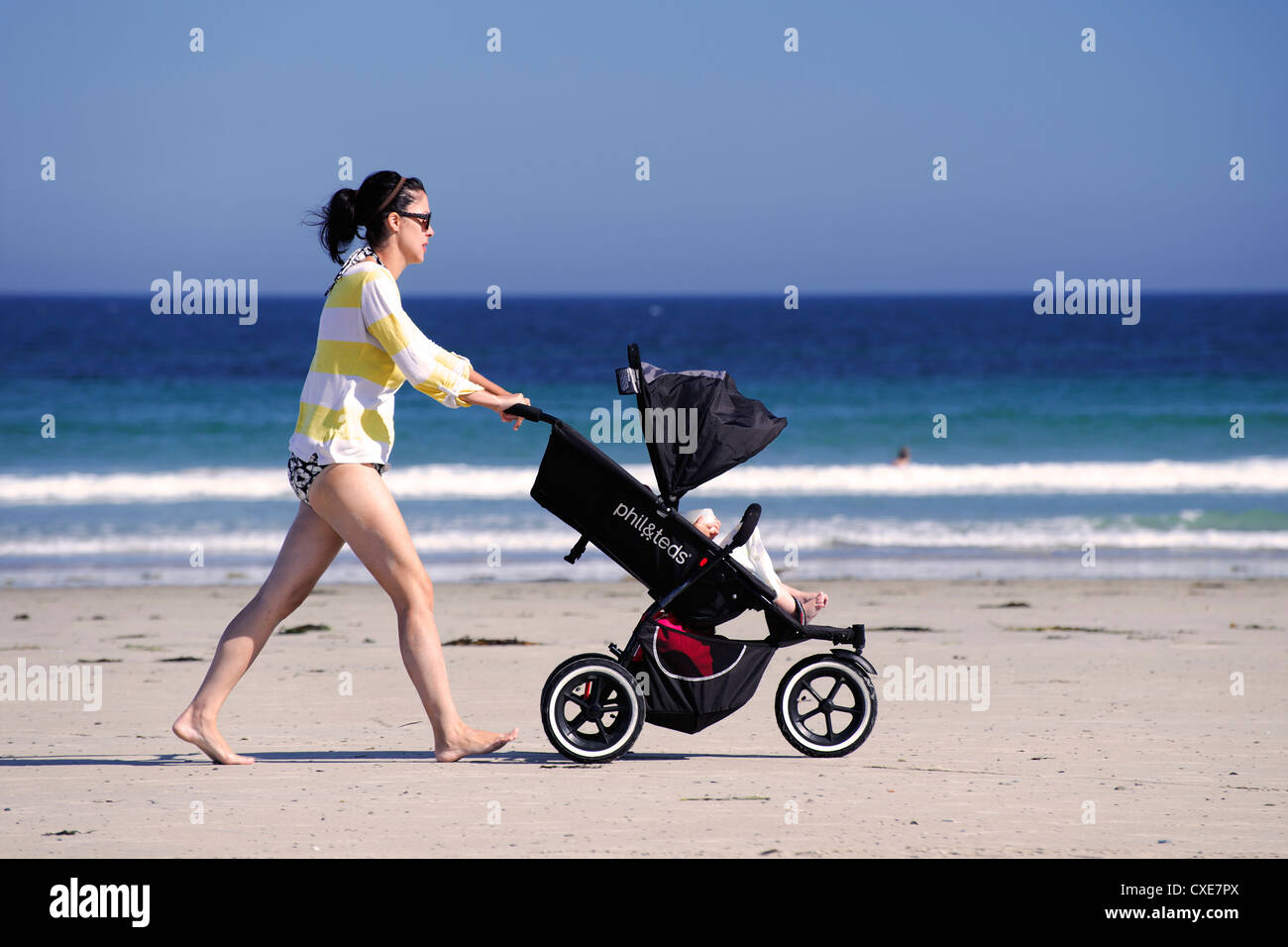 Young woman pushing a stroller on the beach Stock Photo - Alamy