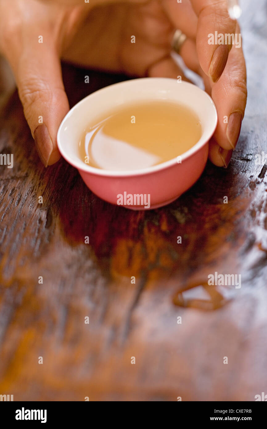 Woman's hand holding small cup of tea Stock Photo - Alamy