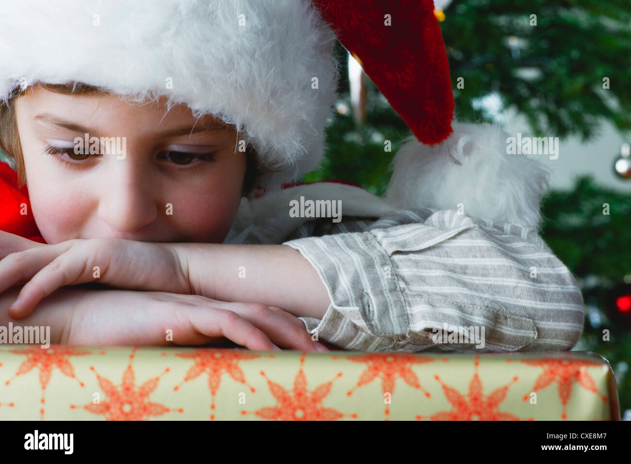 Boy resting head on Christmas present Stock Photo - Alamy