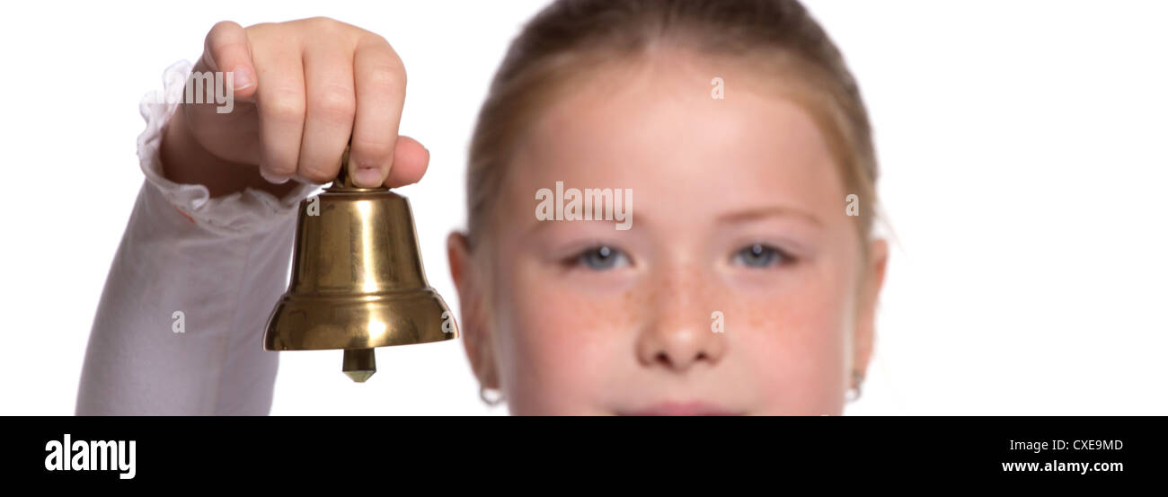 Young school girl ringing a golden bell on white background focused on ...