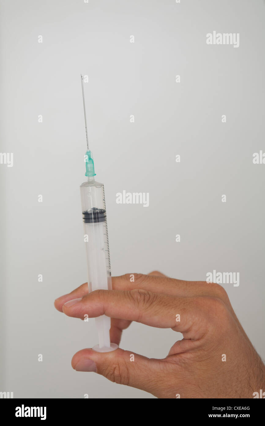 Hand holding syringe Stock Photo - Alamy