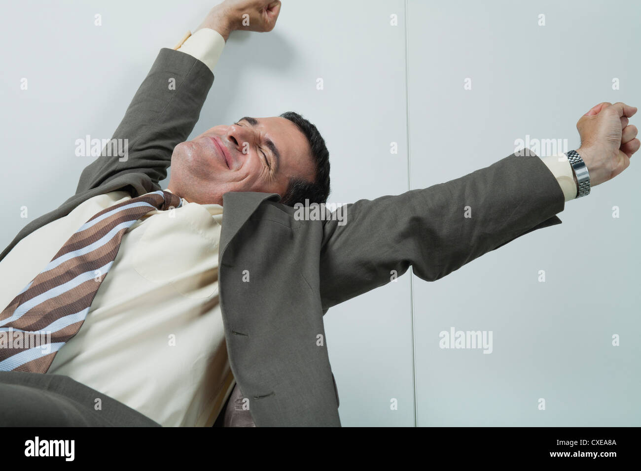 Businessman leaning back, stretching arms Stock Photo - Alamy