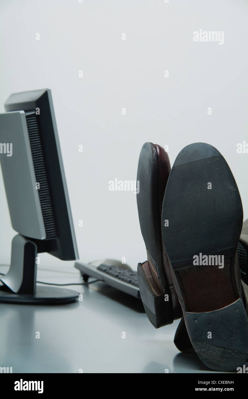 Businessman with feet up on desk in office, cropped Stock Photo - Alamy