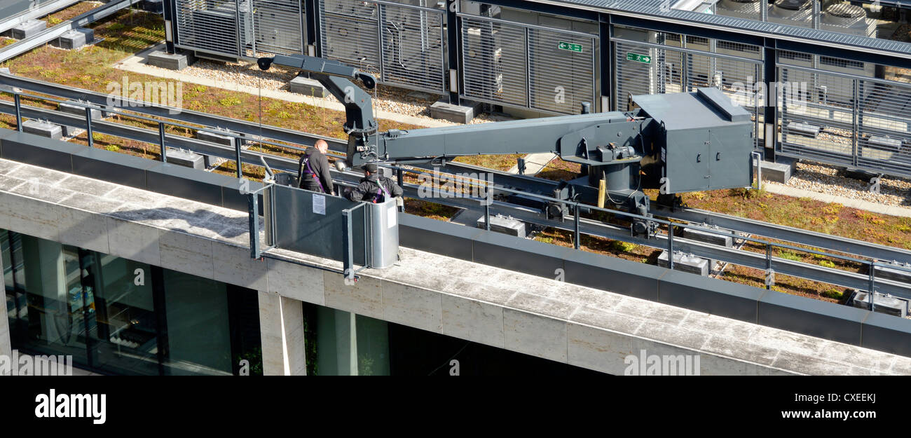 Roof mounted crane and tracks on roof of office building with two men ...