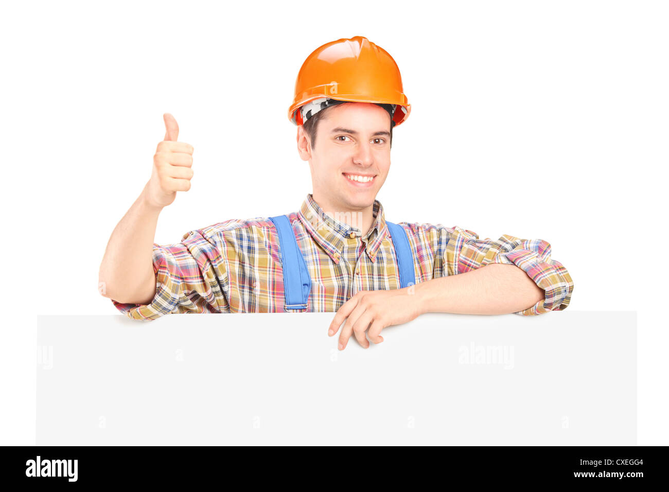 A happy male construction worker posing behind a blank panel giving ...