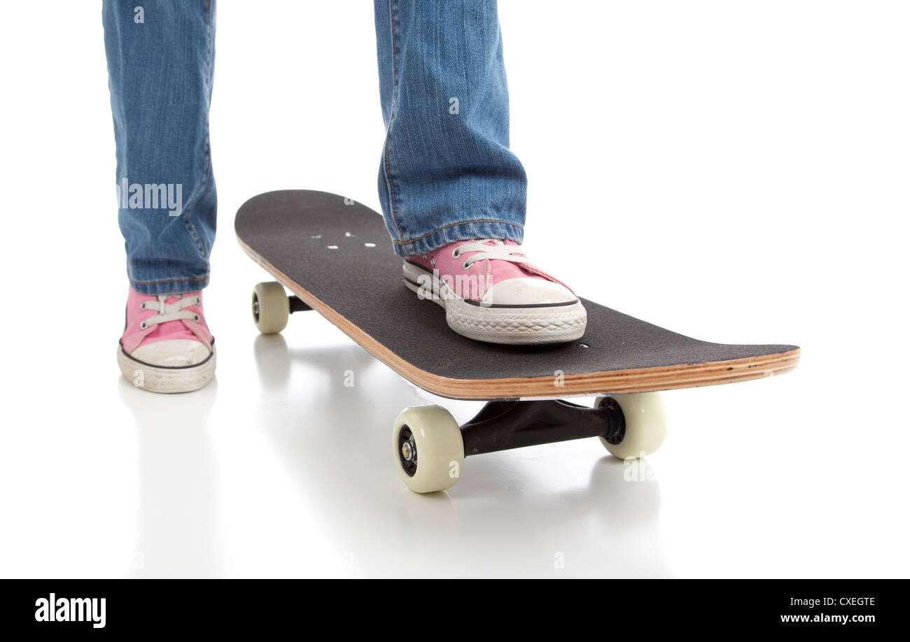 A black skateboard with pink sneakers and jeans on a white background ...