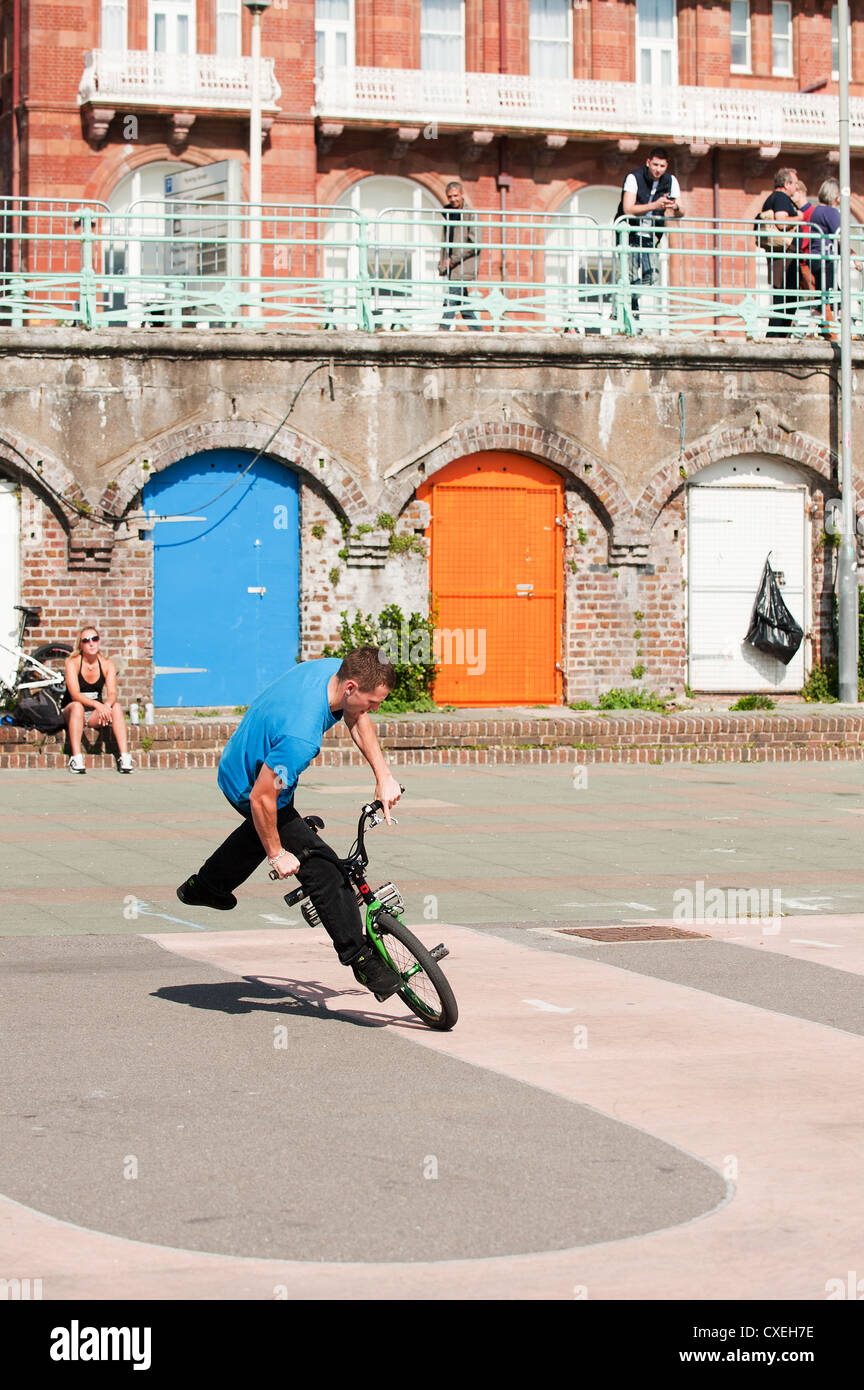 A man performing freestyle tricks tricks on a flatland BMX bicycle ...