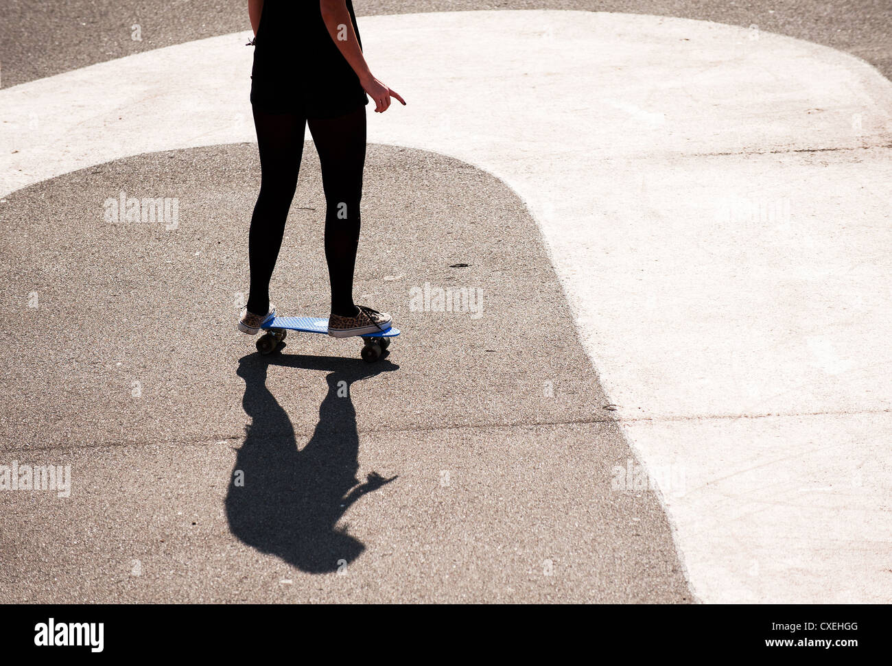 A girl on a skateboard casting her shadow Stock Photo - Alamy