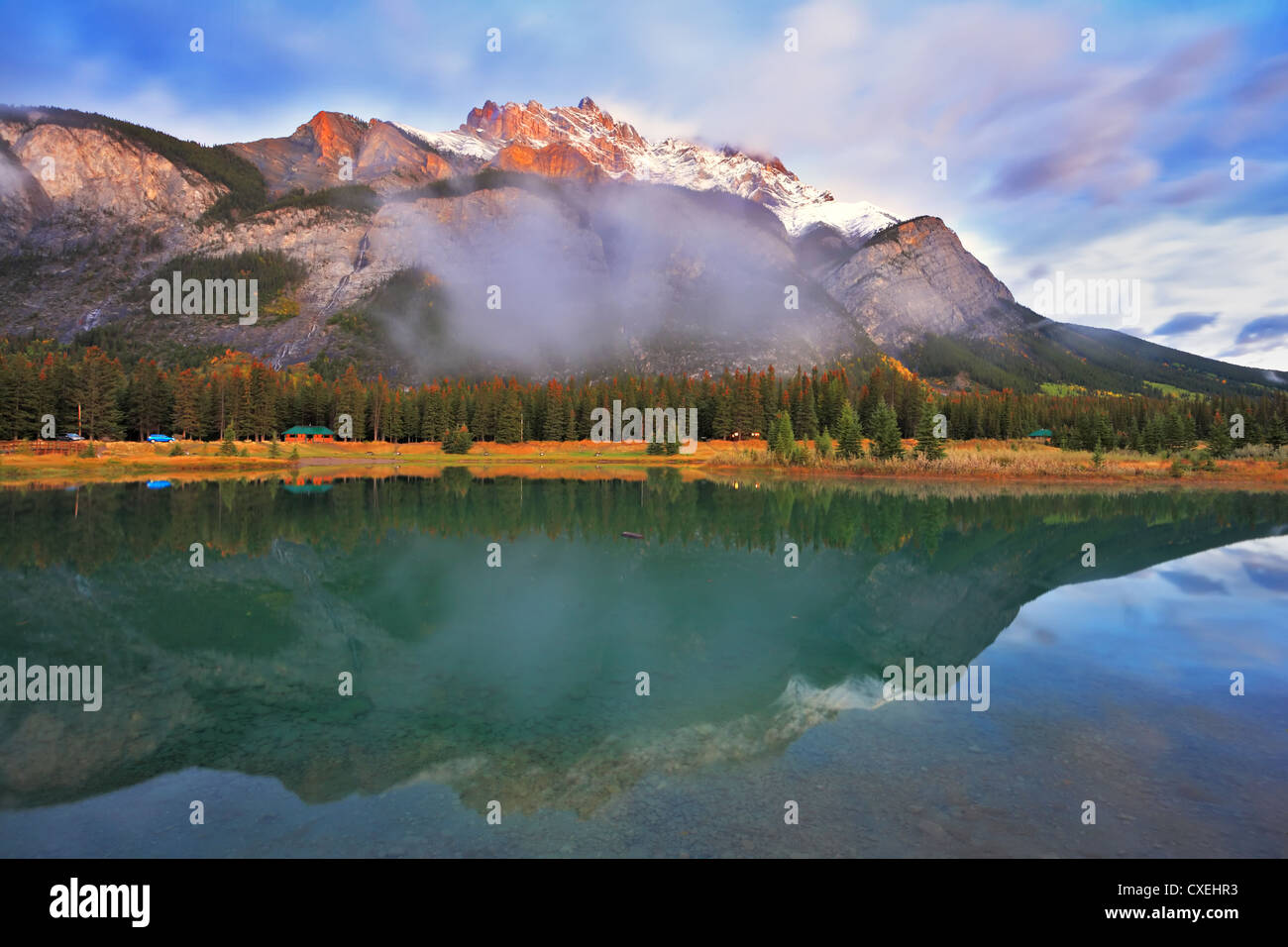 Dark blue cold lake, forest coast and snow mountains Stock Photo - Alamy