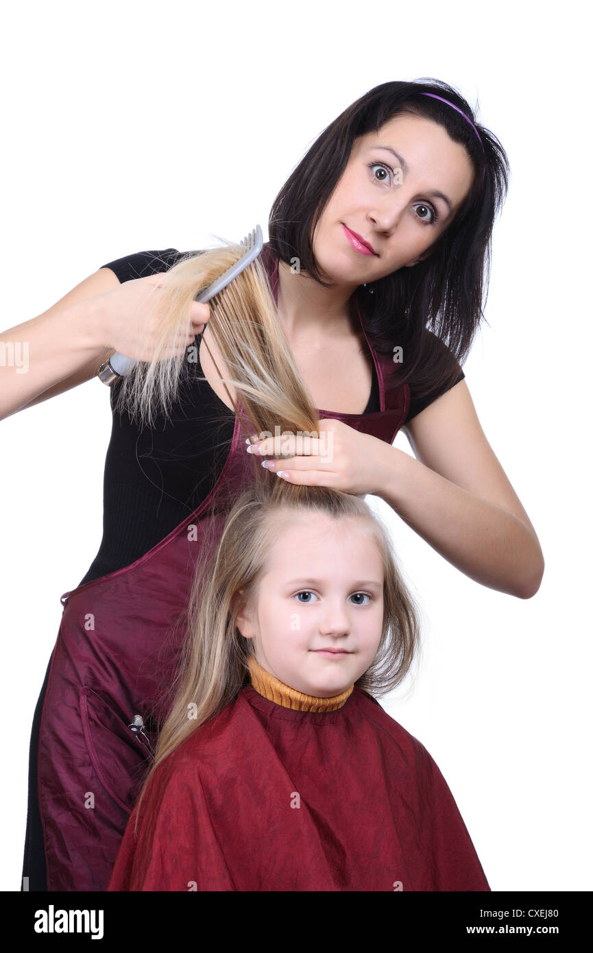 Young woman barber makes hairstyle for a girl isolated on white ...