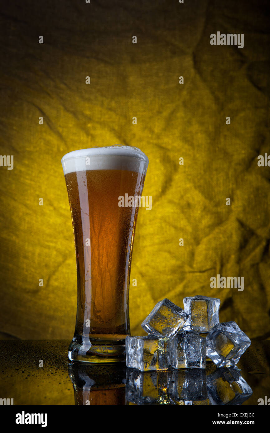 Beer in glass with ice cubes on yellow background Stock Photo - Alamy