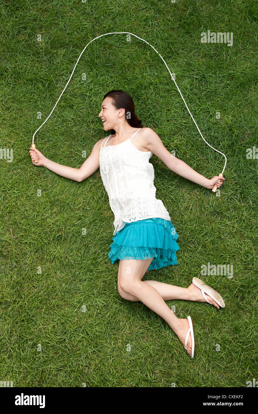 Creative young woman imitating jumping rope on meadow Stock Photo - Alamy