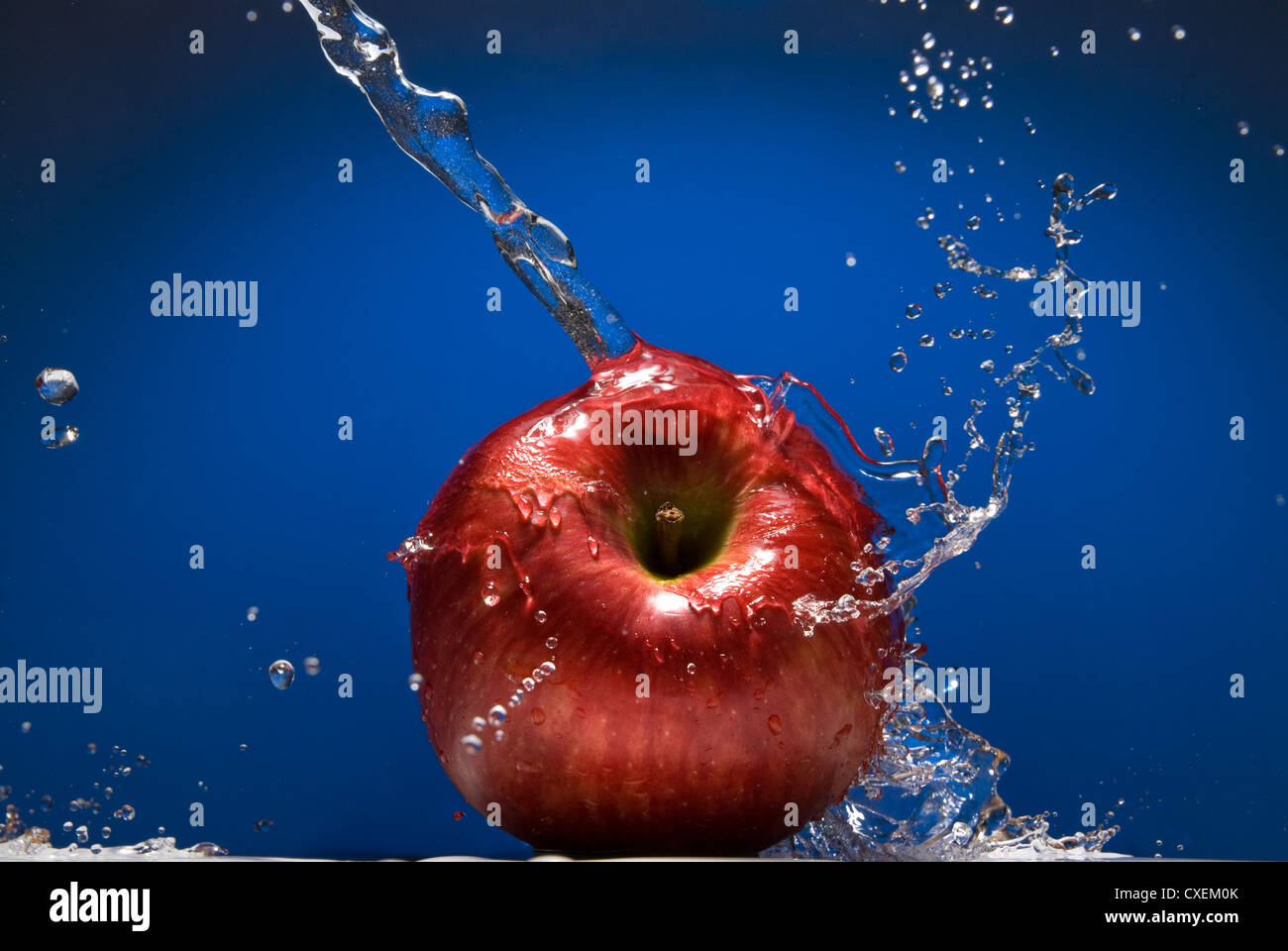 Red apple with water splash on blue background Stock Photo - Alamy