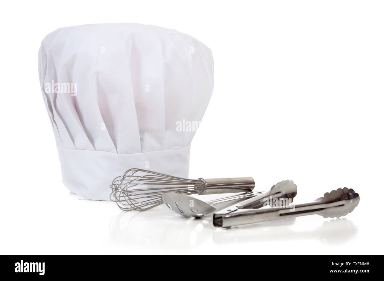 A white chef's hat/toque with assorted serving utensils on a white ...