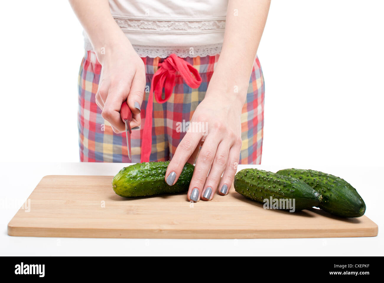 Woman's hands cutting cucumbers on white background Stock Photo - Alamy