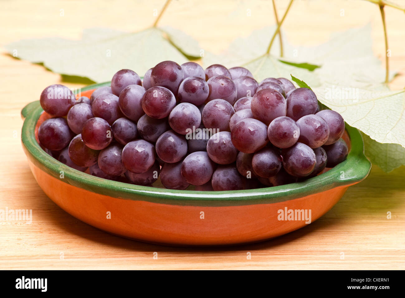Red table grapes and leaves on wooden table Stock Photo - Alamy