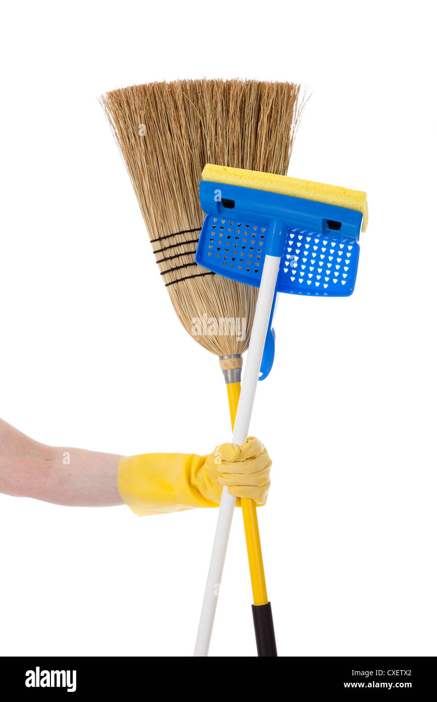 Yellow Rubber gloved hand holding a straw broom and a sponge mop on a ...