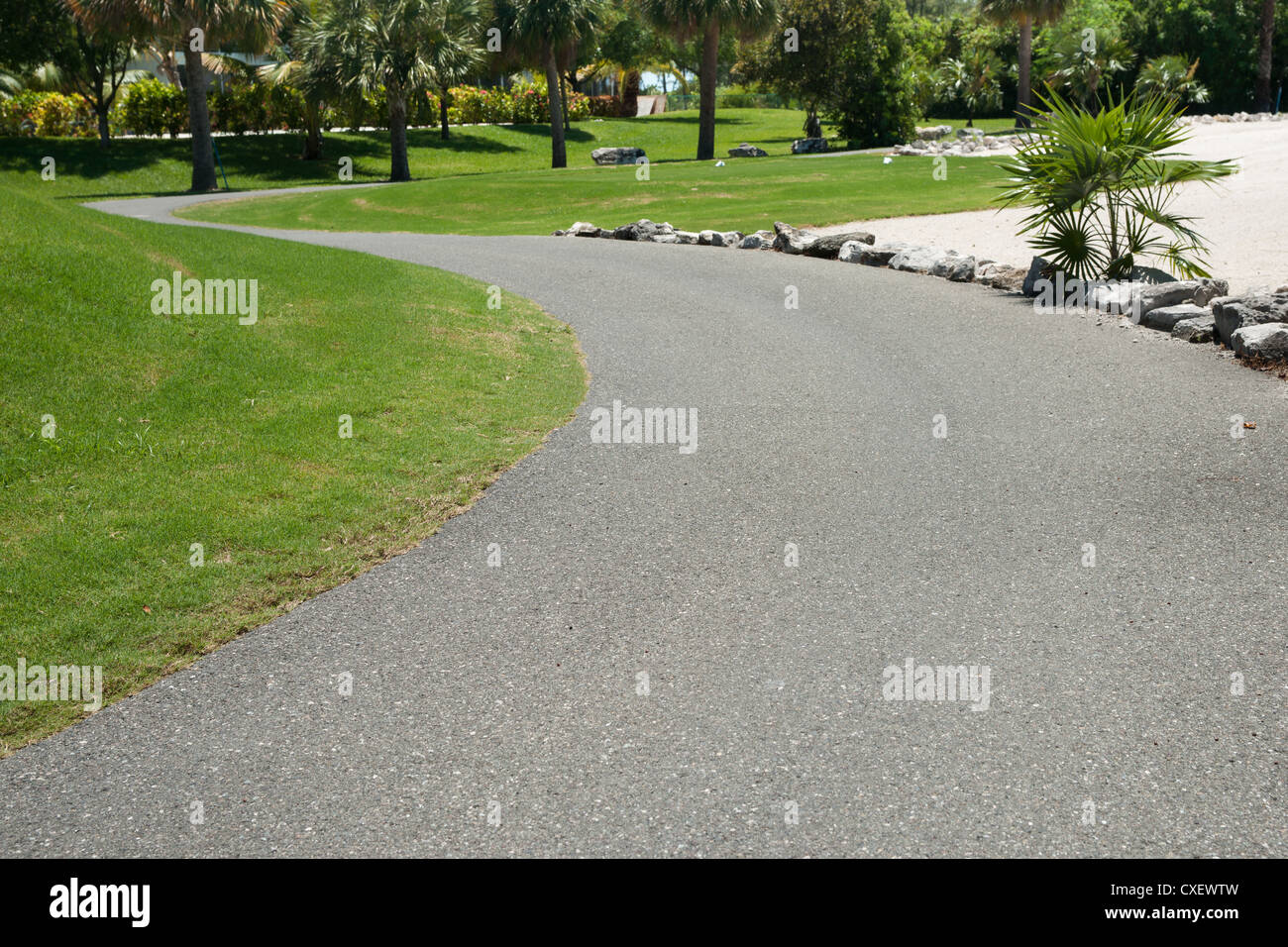 Winding path through the green of a golf green on left and sand bunker ...