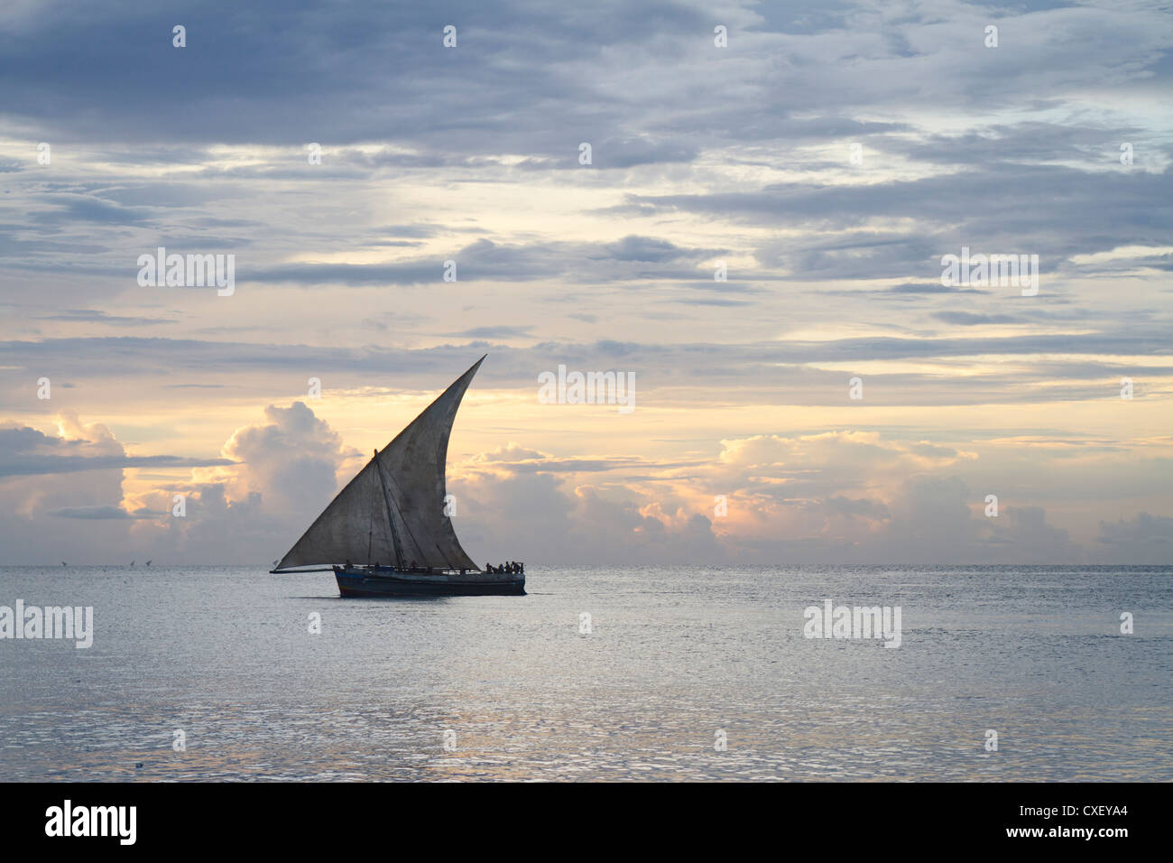 A Traditional Dow Sails Against A Sunset Backdrop in Zanzibar Tanzinia ...